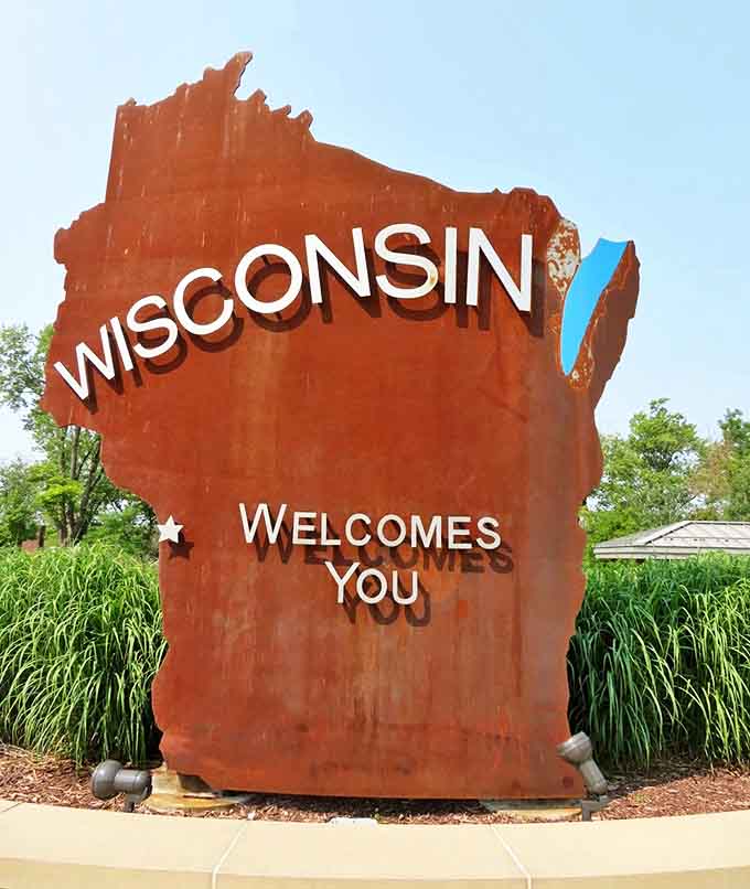 This metal state sign stands as a modern sentinel, welcoming road-weary travelers to the land of brats and Packers fans.