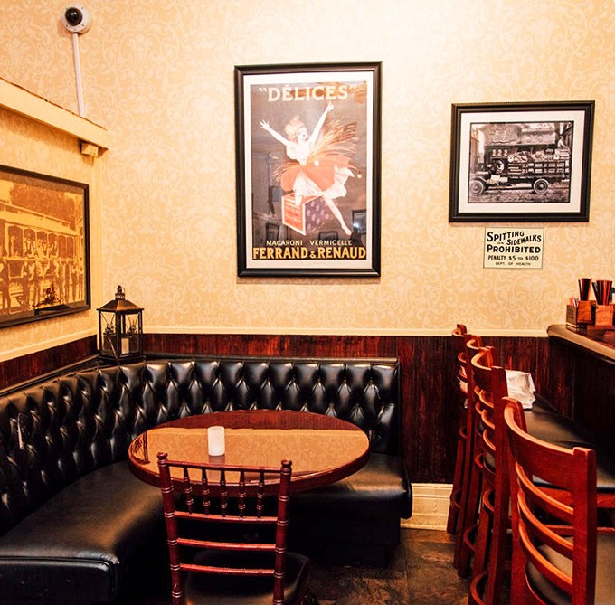 Leather-cushioned privacy in a cozy corner where vintage posters transport you to another era while you savor every bite of the present moment.