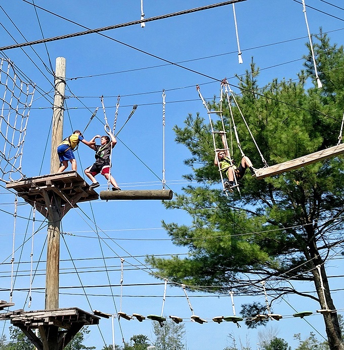 Teamwork makes the dream work! These young adventurers demonstrate perfect form while navigating the high elements course together.