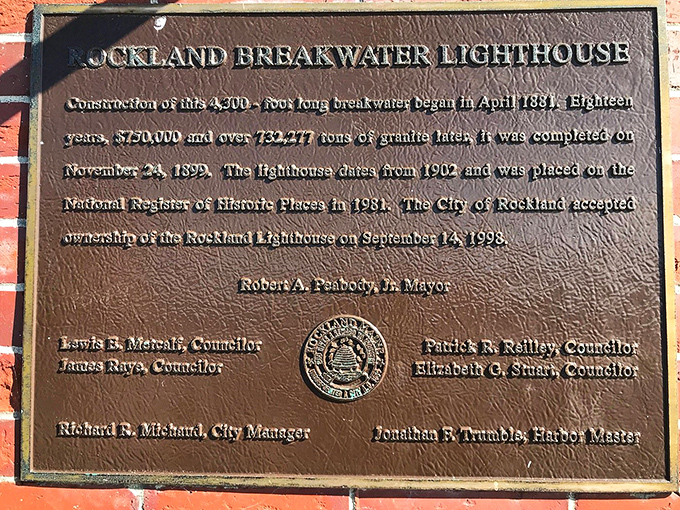 A bronze plaque reveals the breakwater's impressive statistics: 18 years of construction and over 700,000 tons of granite to complete.
