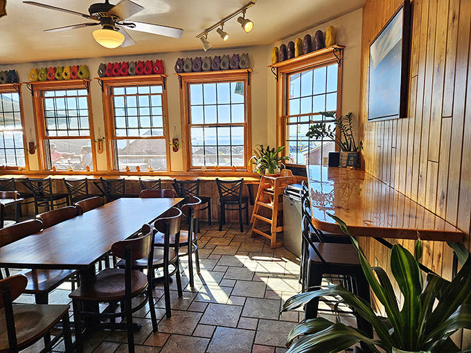 Sunlight streams through windows lined with colorful boots, creating a cheerful atmosphere where every seat offers views worth savoring.