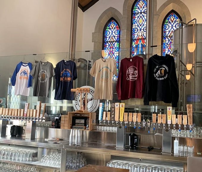 Atwater merchandise hangs against stained glass &ndash; a colorful reminder that you can take home a piece of this unique brewery experience.