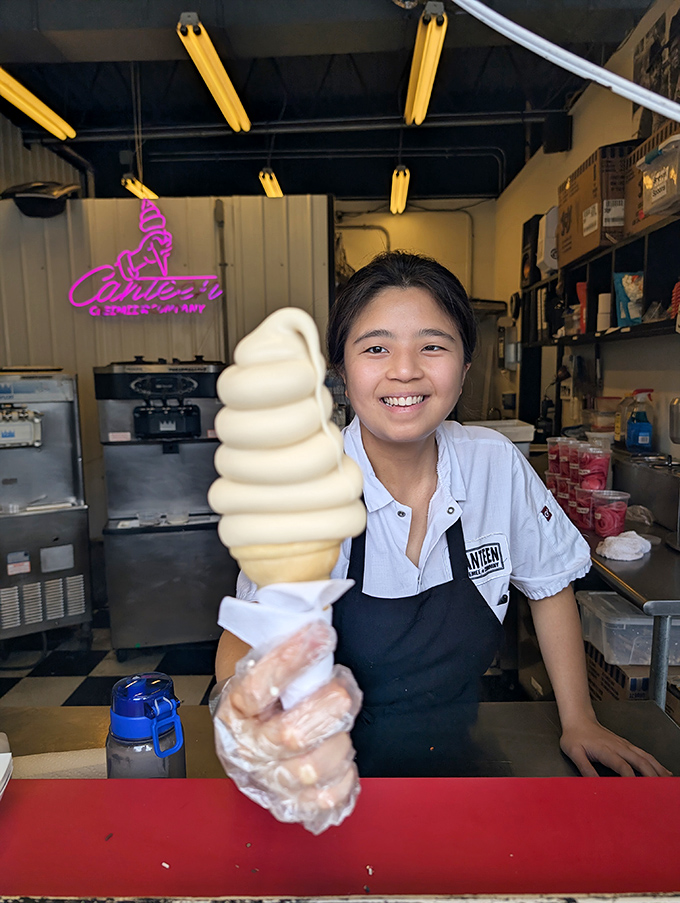The joy of serving perfect creemees is written all over the face of this staff member, proudly displaying a vanilla tower of soft serve perfection.