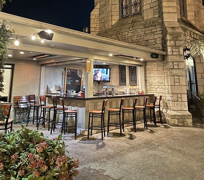 The outdoor bar extends the biergarten experience, offering al fresco sipping against the backdrop of the historic stone church architecture.