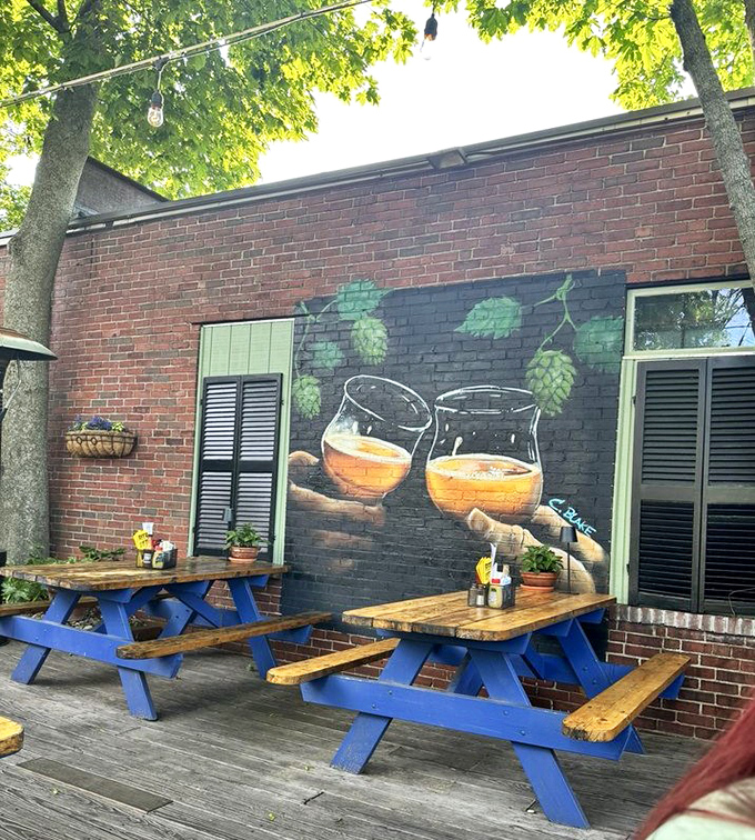 Blue picnic tables under string lights create an outdoor oasis, with beer-themed murals providing the perfect backdrop for summer evenings.