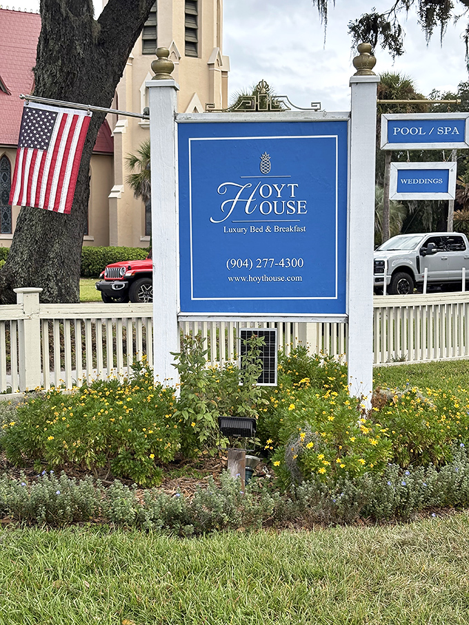 The welcoming sign stands amid blooming gardens, promising luxury and relaxation to weary travelers seeking Southern comfort.