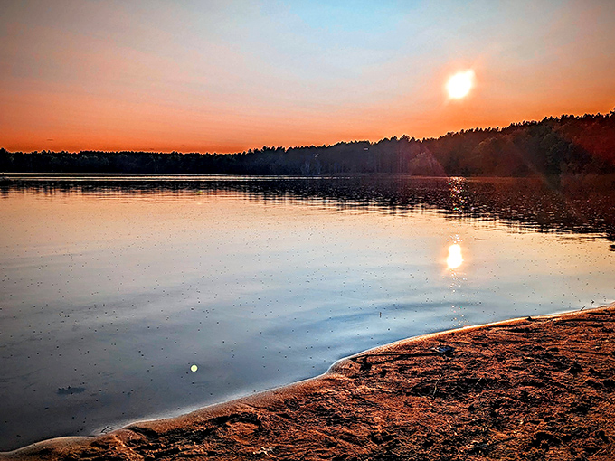 The day's final light creates a golden pathway across waters so still they capture every nuance of the fading sun.