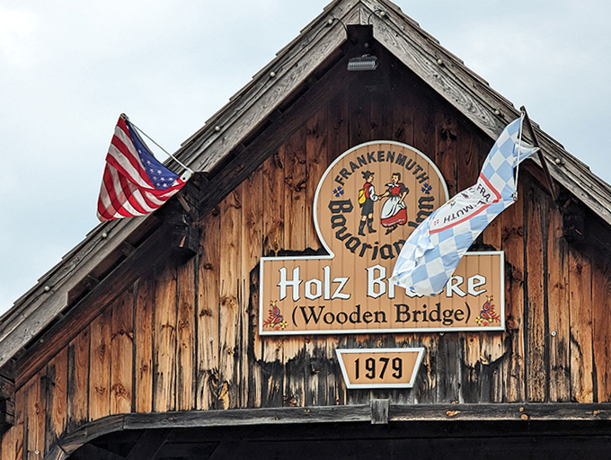 Proudly displaying its heritage, the bridge's signage announces "Holz Br&uuml;cke" alongside Bavarian imagery, a wooden ambassador of Michigan's Little Bavaria since 1979.