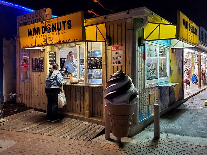 Meaney's wooden shack glows with promise at night, a beacon of mini donut delight for beachgoers seeking sweet treasures.