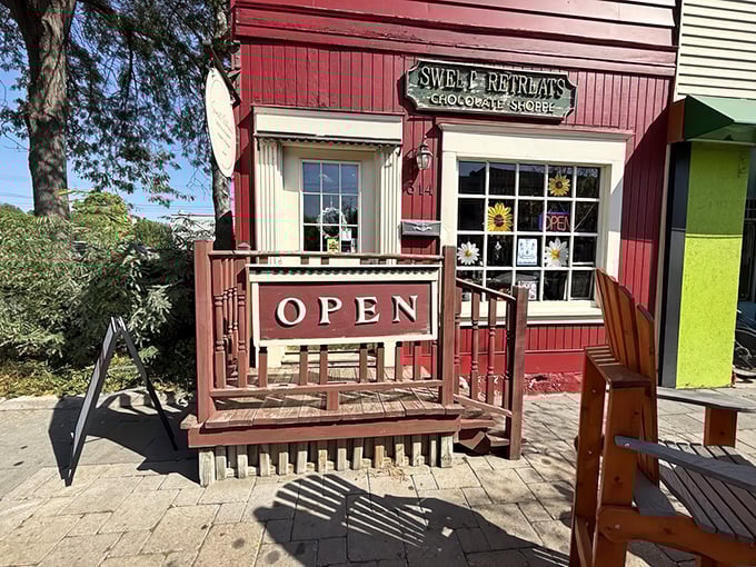 Sweet Retreats' charming red storefront welcomes chocolate lovers with its vintage "OPEN" sign and cozy porch &ndash; a storybook shop come to life!