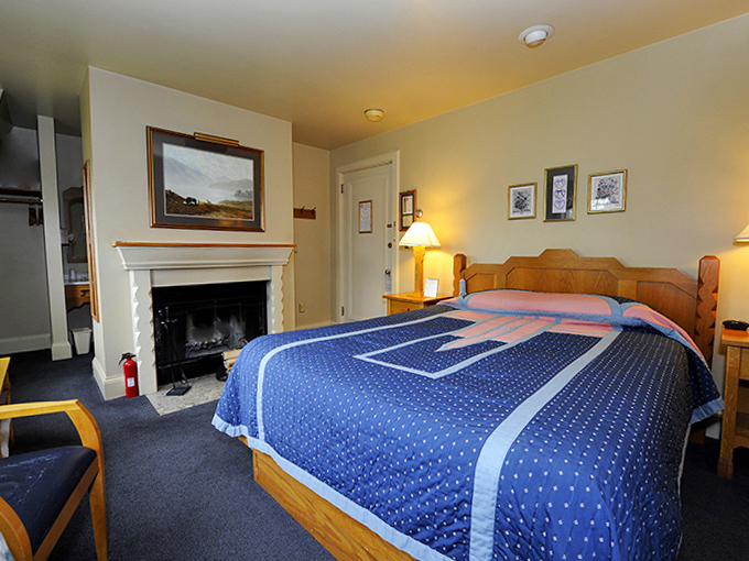 A cozy bedroom sanctuary where modern comfort meets vintage charm – complete with a fireplace that whispers tales of northwoods winters past.