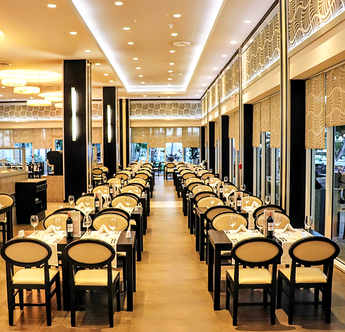 The dining room gleams with elegant simplicity – those cream chairs aren't just stylish, they're strategically designed to accommodate your "buffet posture."