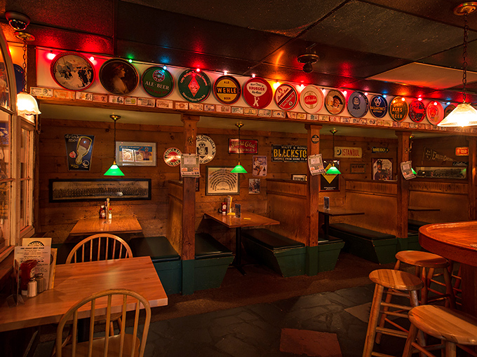 Wooden booths bathed in warm light create intimate dining nooks, while vintage beer trays overhead tell stories of brews gone by.