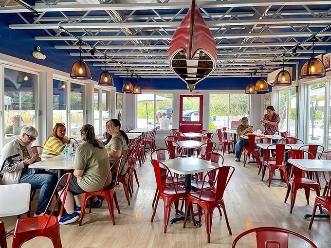 Inside, nautical charm meets practical comfort with bright red chairs and a hanging canoe that says "yes, we're serious about seafood."