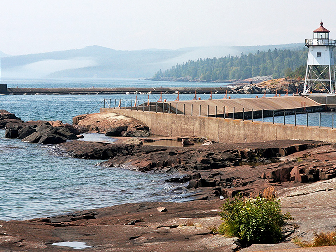 The lighthouse stands sentinel at the harbor entrance, a postcard-perfect scene that's been guiding sailors and capturing hearts for generations.