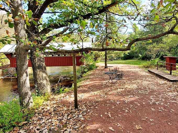 Dappled sunlight plays across rustic picnic tables beside the historic Red Mill, where the gentle stream whispers stories of simpler times.