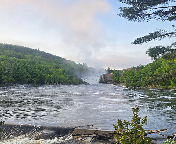 The misty morning view of Rumford Falls showcases Maine's tallest waterfall in all its glory, with the historic mill building standing sentinel.