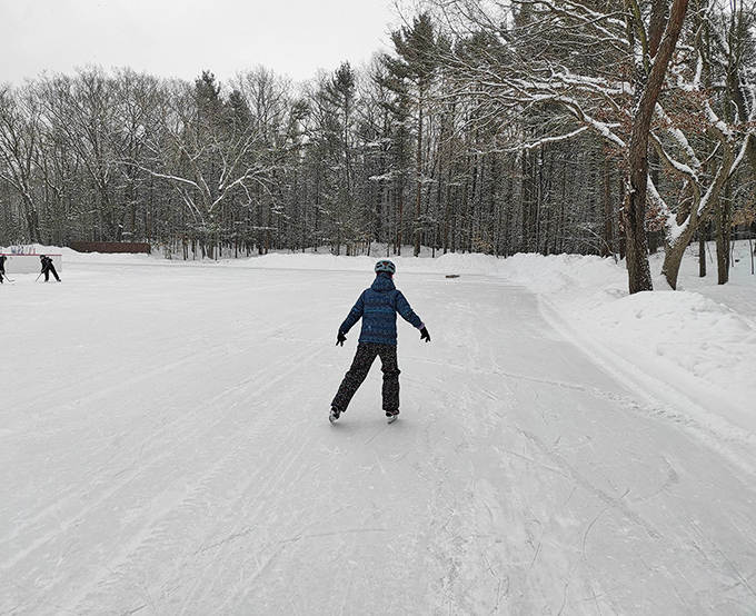 Gliding across natural ice under open skies beats any mall rink – just look at that perfect Michigan winter backdrop!