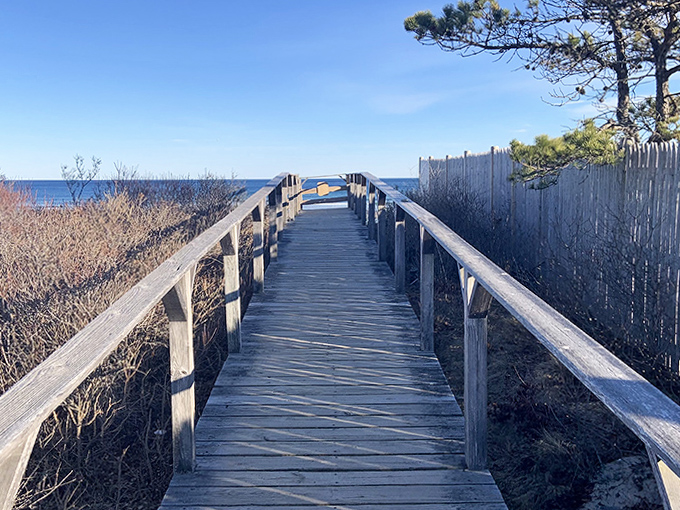 The wooden boardwalk beckons like a runway to paradise, guiding visitors through protected dunes to seaside splendor.