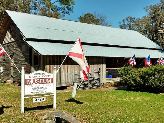The Micanopy Historical Society Museum welcomes history buffs with its rustic wooden exterior and proudly displayed flags.