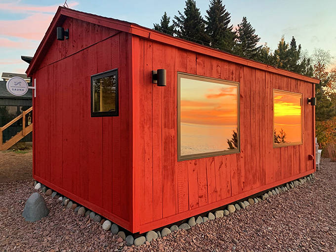 The vibrant red sauna cabin stands like a cheerful sentinel against the shoreline, promising warmth even on Minnesota's chilliest days.
