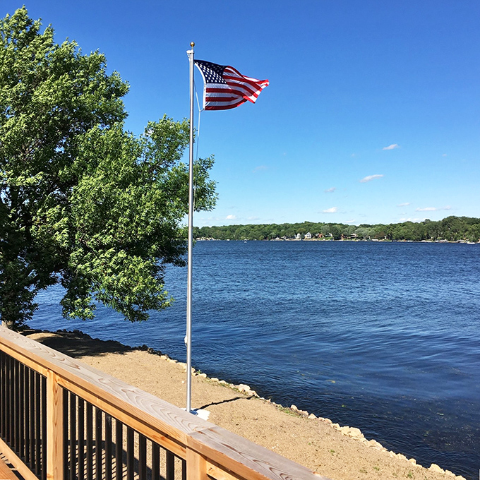 The American flag waves proudly against a perfect blue sky, marking your own private piece of Minnesota paradise.