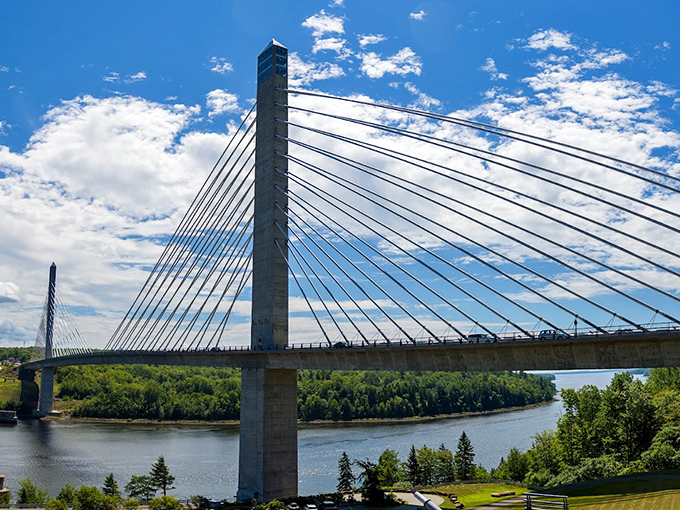 Sunlight plays across the bridge's cables, creating a geometric dance of light and shadow against the backdrop of Maine's endless blue sky.
