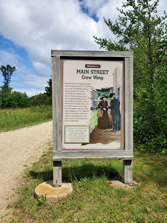 The weathered sign welcomes visitors to Main Street Crow Wing, where history whispers through every illustrated detail.
