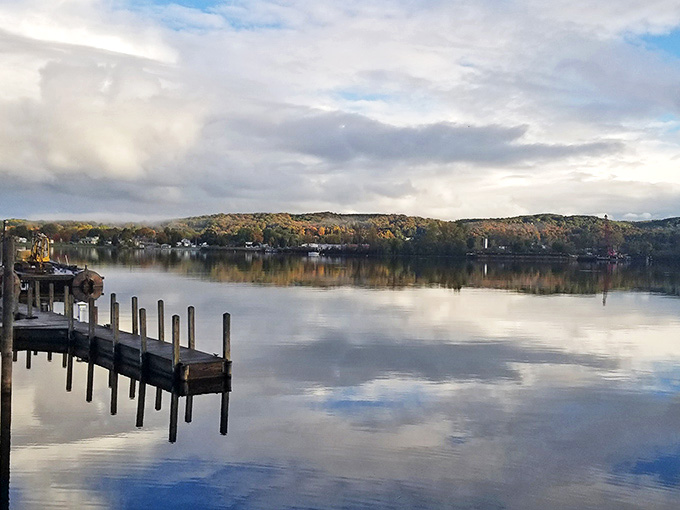 A wooden dock reaches into still waters that mirror the sky, creating nature's perfect symmetry in this peaceful Michigan haven.