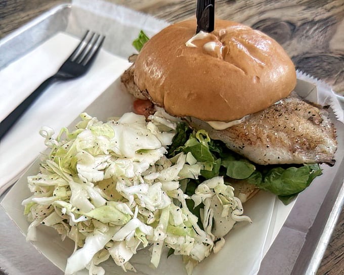 This grouper sandwich isn't just lunch – it's a Florida tradition served on a bun with a side of coleslaw perfection.
