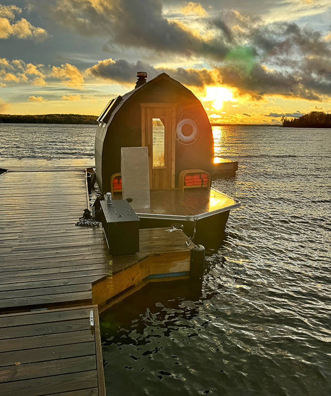 Golden hour transforms the floating sauna into a silhouette against the fiery Minnesota sunset, nature's perfect mood lighting.