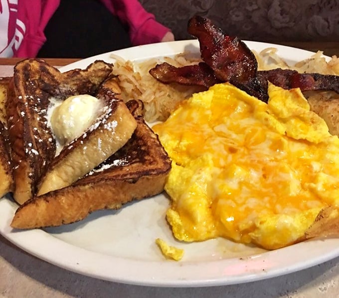 The French Hook Up: Golden-brown French toast meets fluffy scrambled eggs and crispy bacon – a breakfast trio performing in perfect harmony on this generously portioned plate.