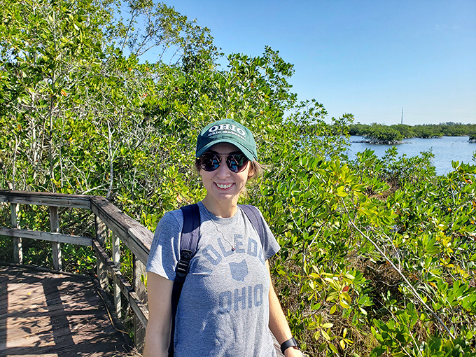 A happy explorer pauses along the trail, sporting the essential Florida nature-watching uniform: hat, sunglasses, and an adventurous spirit.