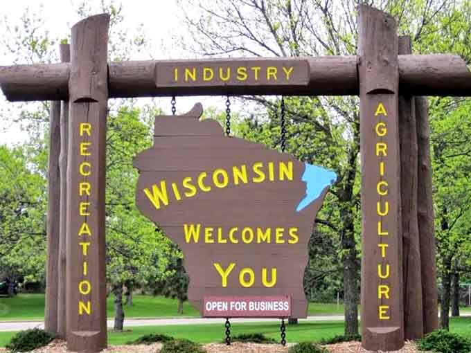 This rustic wooden welcome sign embodies Wisconsin's spirit &ndash; sturdy, natural, and warmly inviting to all who pass by.