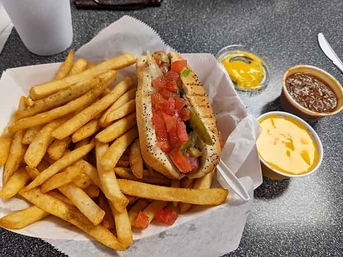 Behold the Chicago-style masterpiece: more toppings than a Supreme Court case, perfectly balanced on a poppy seed bun that somehow holds it all together like edible architecture.
