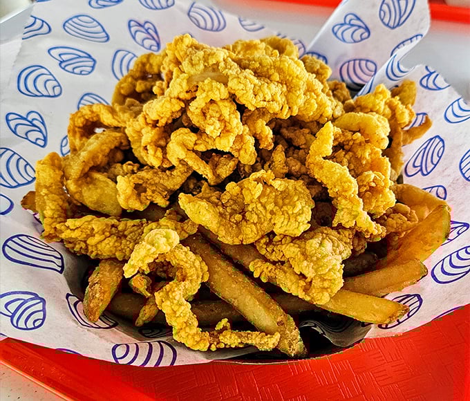 Golden-fried clam strips piled high atop crispy fries &ndash; a mountain of seafood perfection worth climbing.