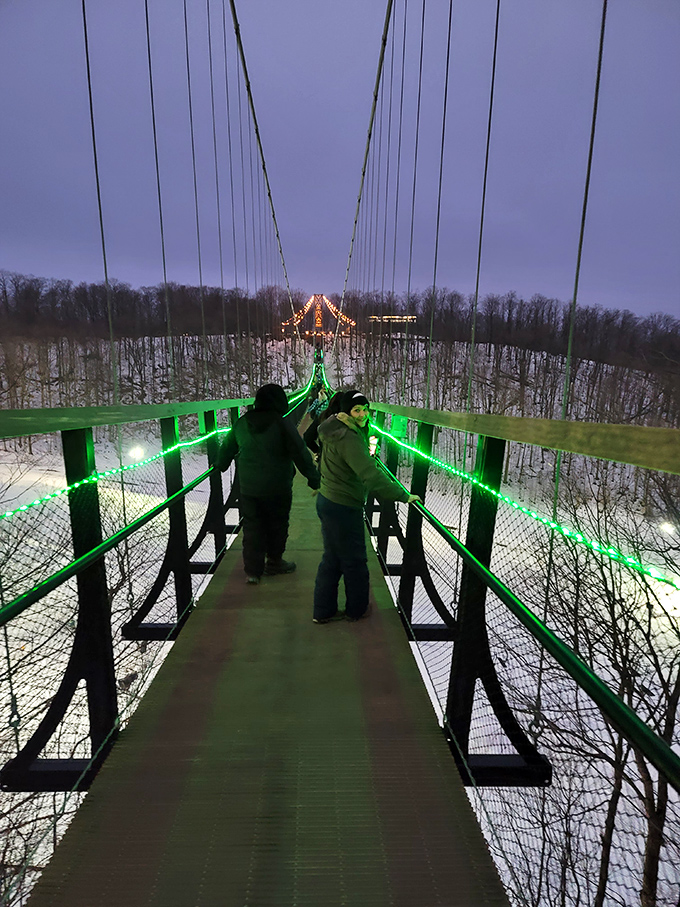 Brave souls venture across the illuminated pathway, their silhouettes dwarfed by the vastness of Michigan's twilight landscape.