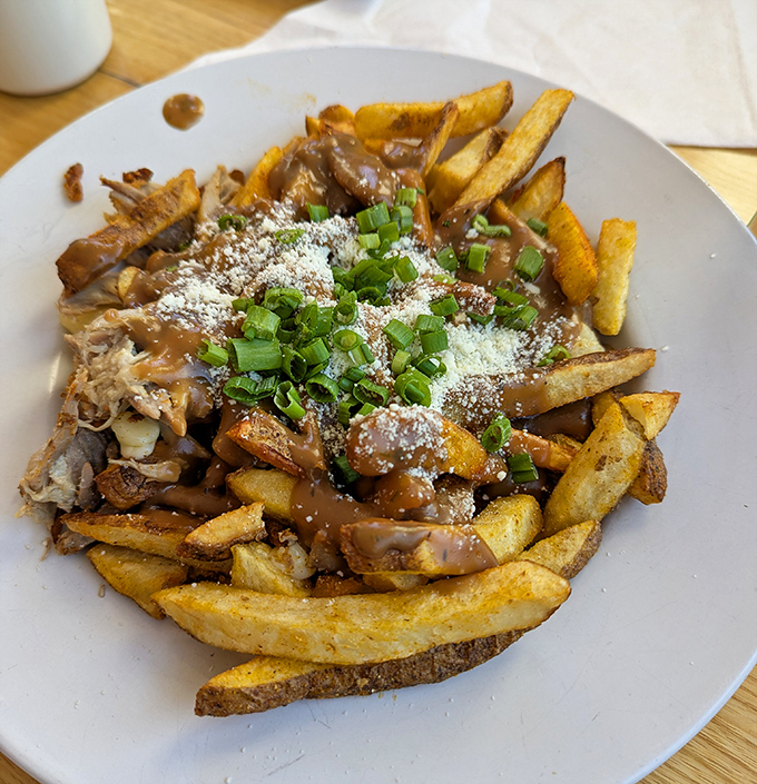 Duck confit poutine that would make Canadians weep with joy &ndash; golden fries, savory gravy, melty cheese curds, and tender duck creating a perfect harmony.