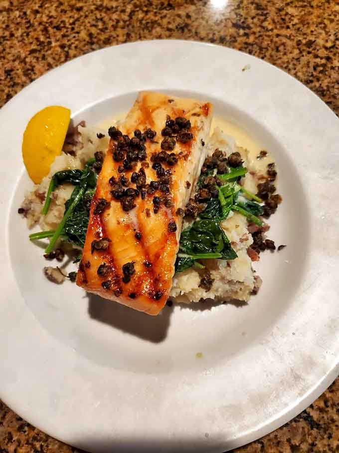 Grilled salmon done right: perfectly charred outside, tender inside, sitting on a bed of rice with spinach and lentils that actually taste good.