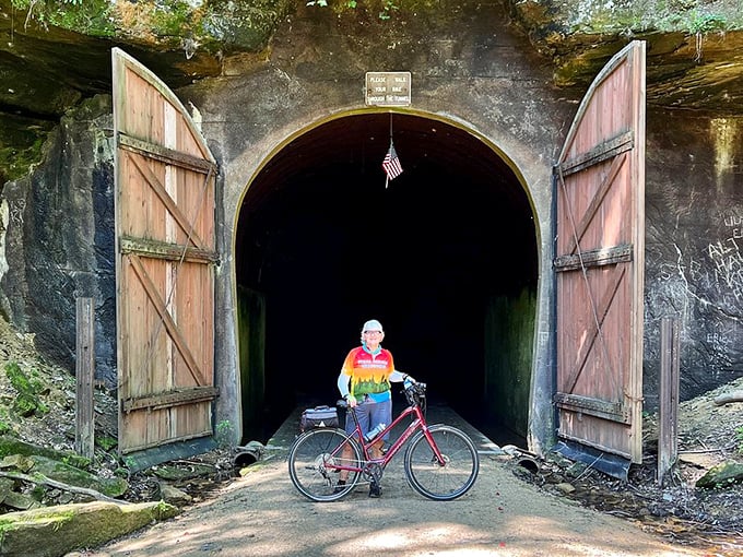 A colorful cyclist pauses at the historic tunnel entrance &ndash; the perfect scale comparison for these massive passageways.