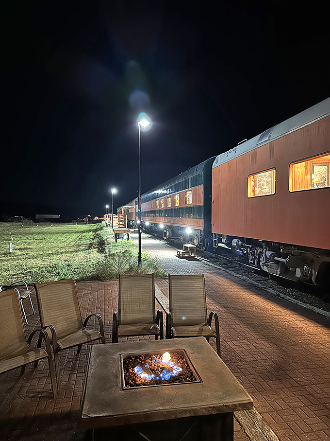Nighttime magic unfolds as the train glows against the darkness, a fire pit promising stories under starlight.