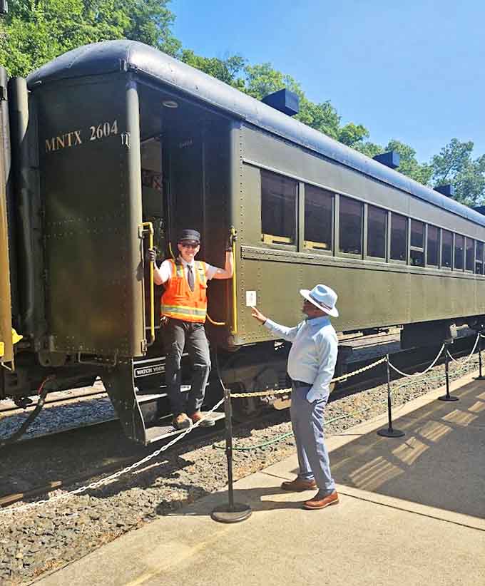"All tickets, please!" A conductor in period-appropriate attire adds authentic charm to the experience, sharing railroad knowledge with an enthusiastic visitor.