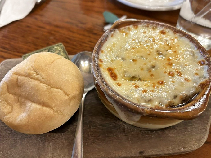 A bubbling cauldron of sweet caramelized onions beneath a golden crown of melted cheese that stretches dramatically with each spoonful.