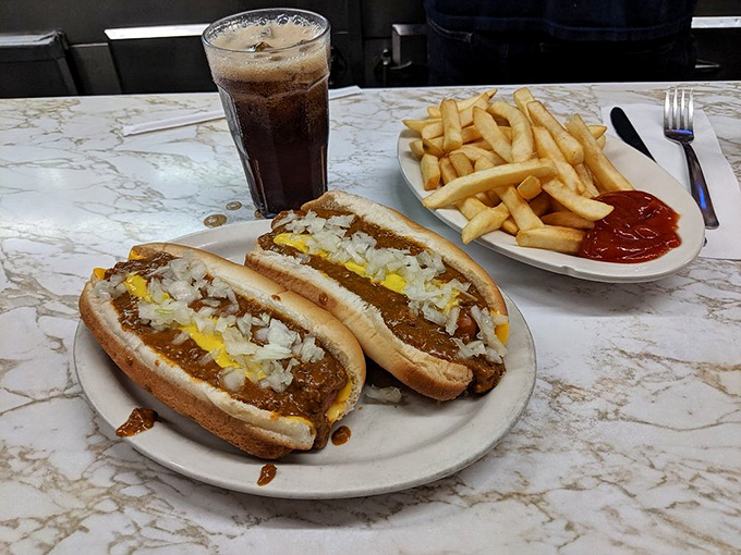 The Detroit Coney experience in its full glory: two chili-smothered dogs flanked by golden fries and a cold soda to cut the richness.