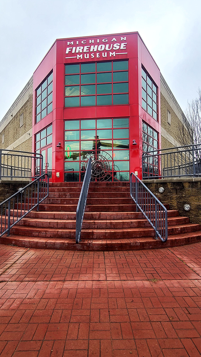 The Michigan Firehouse Museum's bold red exterior signals its past life, now preserving firefighting history behind dramatic glass windows.