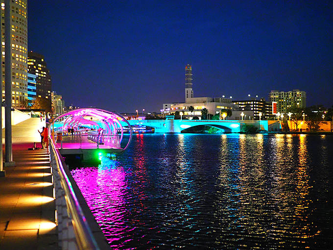 The city skyline puts on its evening jewelry, with buildings twinkling like vertical constellations reflected perfectly in the Hillsborough River's dark mirror.
