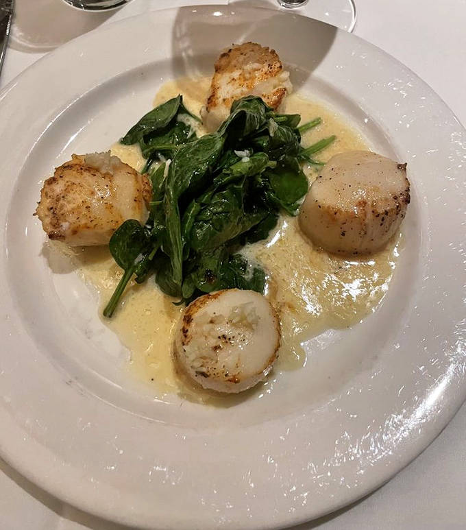 Pan-seared scallops dance with fresh spinach in a delicate sauce &ndash; proof that sometimes the simplest preparations yield the most extraordinary results.