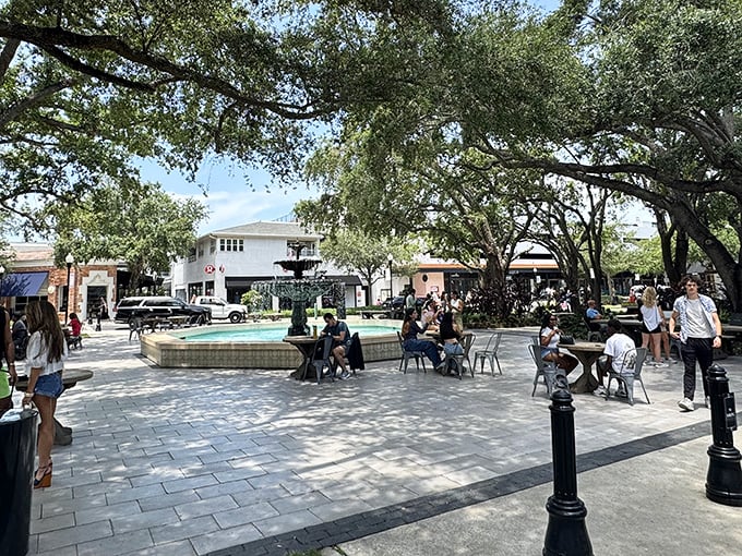 The village square buzzes with conversation and laughter as visitors gather around the fountain, turning strangers into temporary neighbors in this outdoor living room.