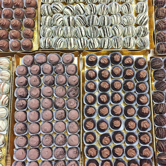 Handcrafted truffles line up like soldiers ready for duty, each one a tiny masterpiece of chocolate perfection waiting to be discovered.