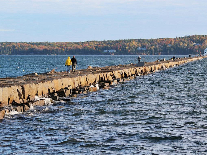 Adventurous souls navigate the 4,300-foot breakwater, where massive granite blocks create a pathway seemingly floating on Penobscot Bay.